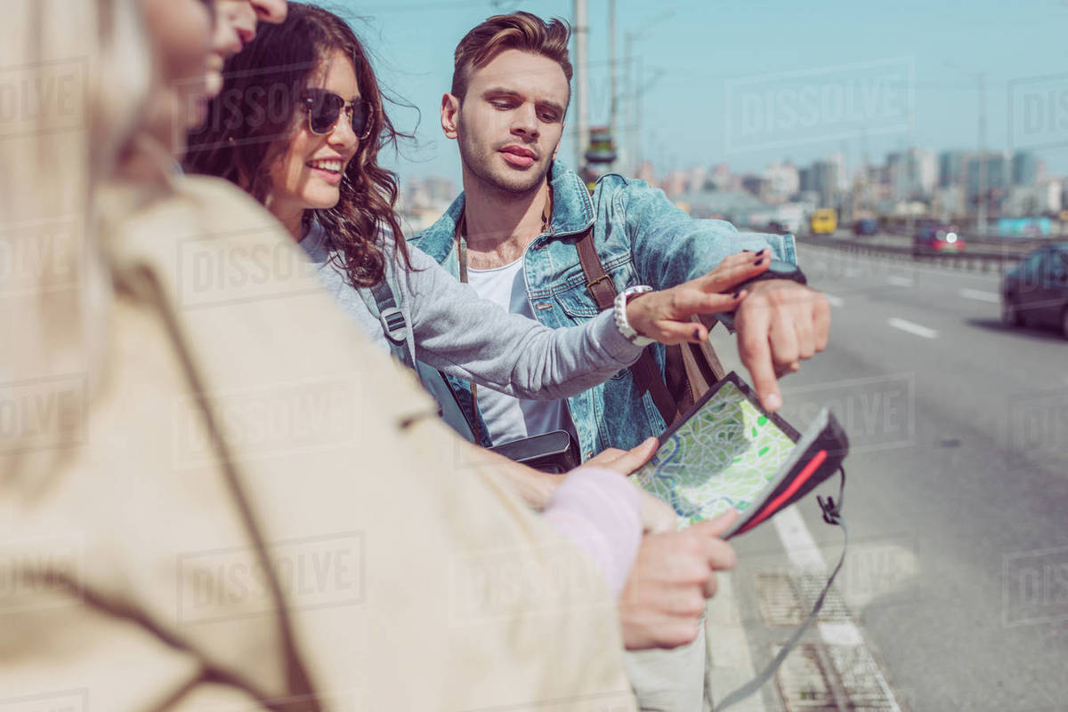 Partial view of tourists looking for destination on map during trip ...