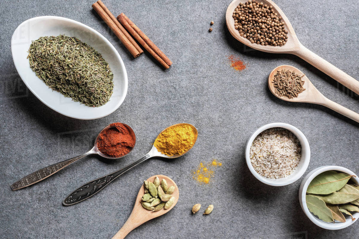 Top view of various aromatic dried seasonings in bowls and spoons on ...