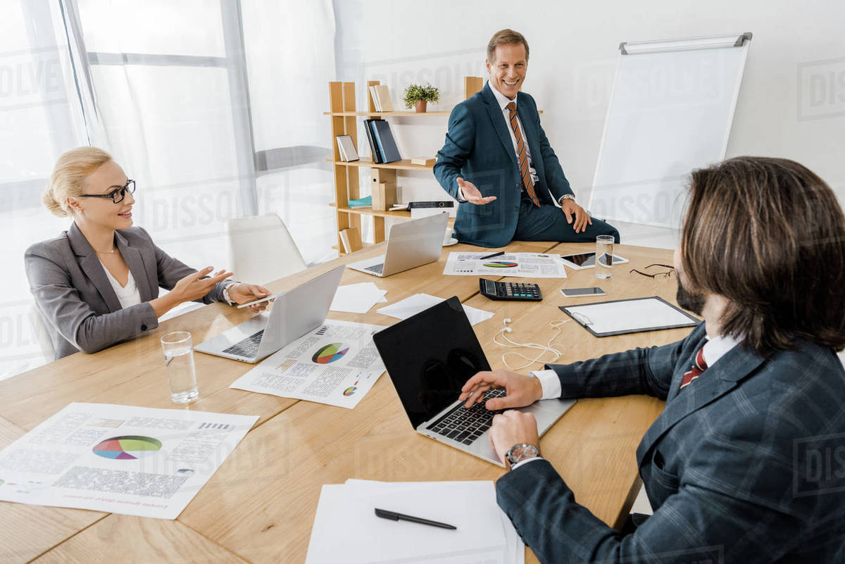 Business people sitting at table and talking during meeting in office ...