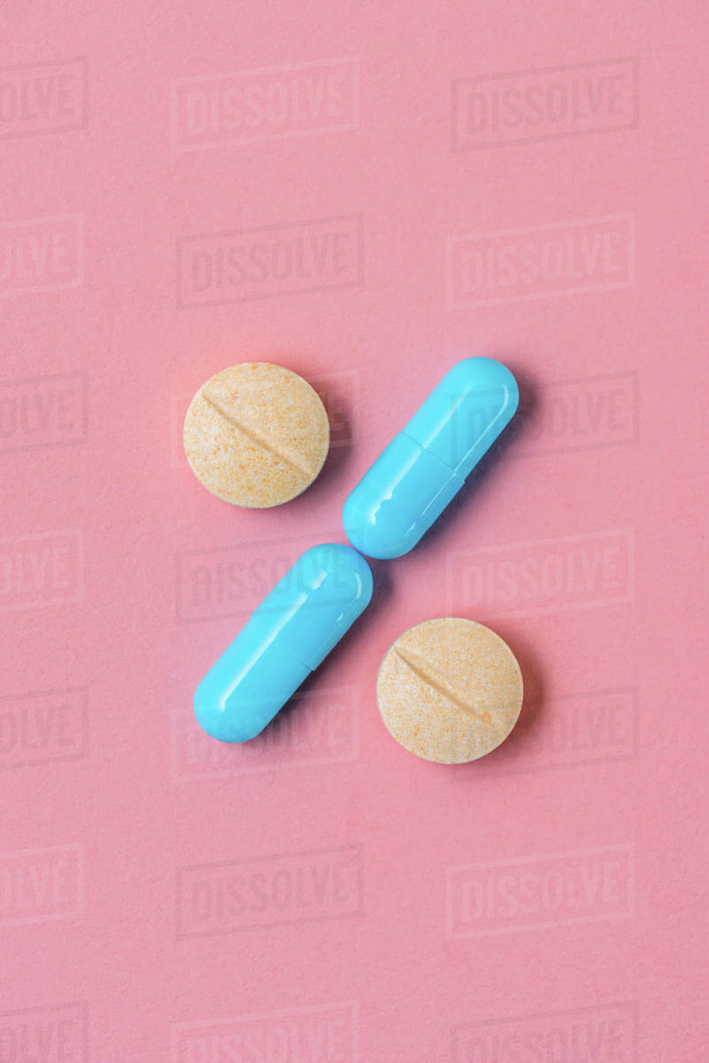 Top view of percent sign made of pills on pink - Stock Photo - Dissolve