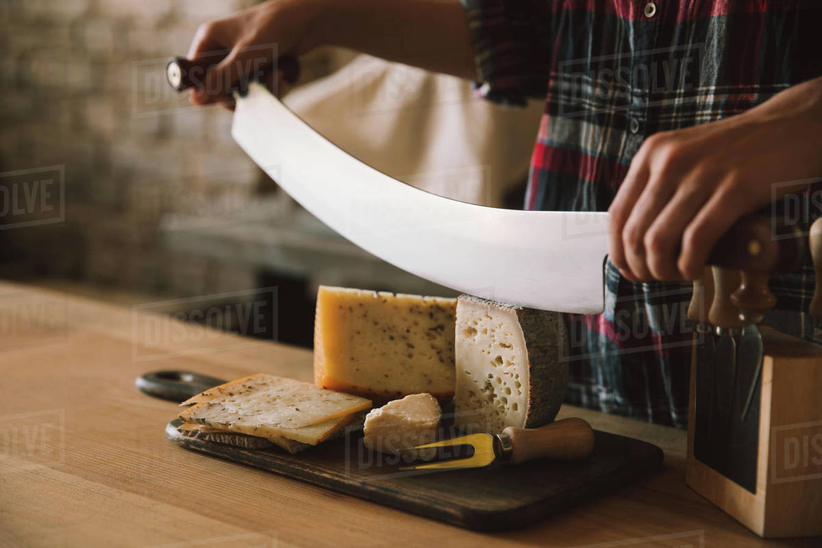 Cropped shot of woman cutting delicious cheese with double handled ...