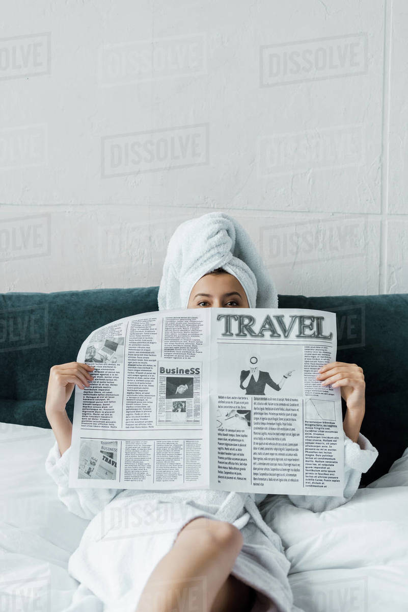 Young woman hiding behind travel newspaper in the morning - Royalty ...
