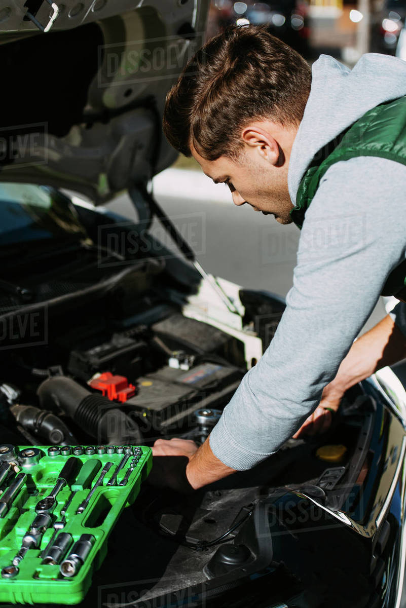 Young man with toolbox fixing broken car engine - Royalty-free Stock ...
