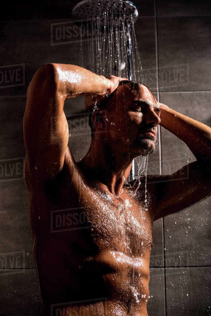 Low angle view of adult man taking shower in morning - Royalty-free Stock Photo | Dissolve