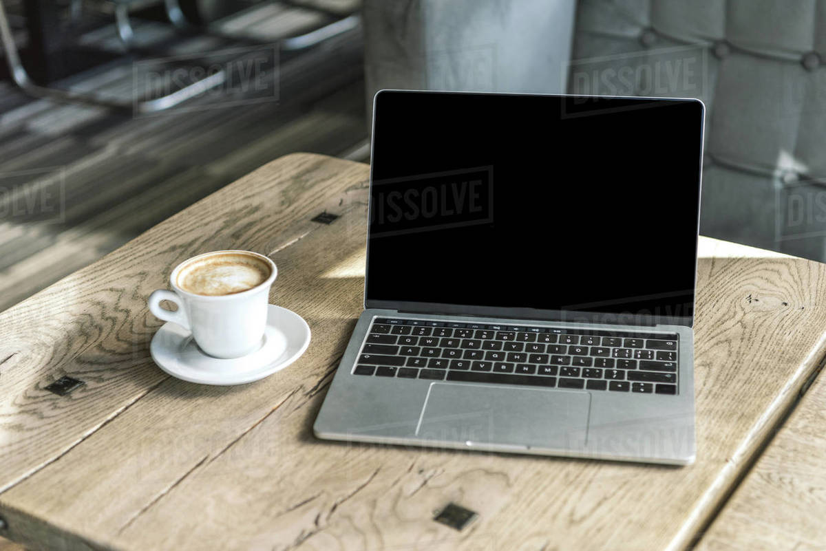 Cup of coffee and laptop with blank screen on rustic wooden table at ...