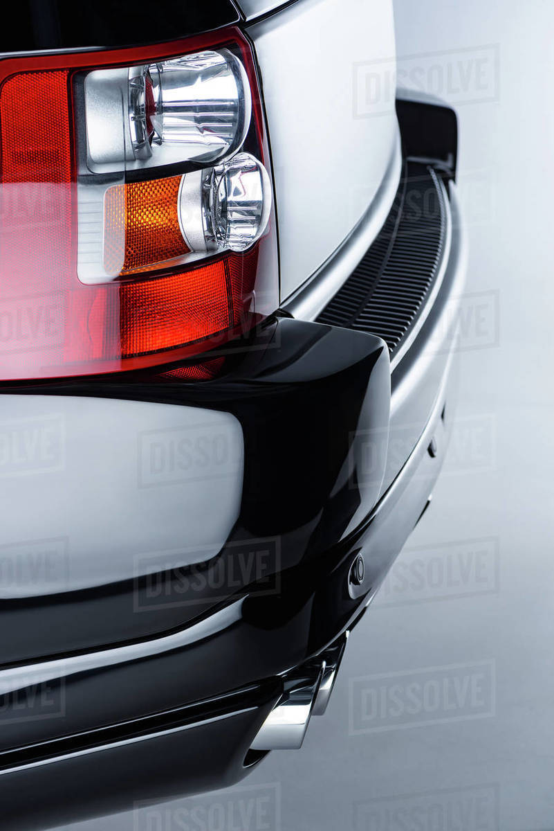 Close up view of rear headlight of luxury black car on grey backdrop ...