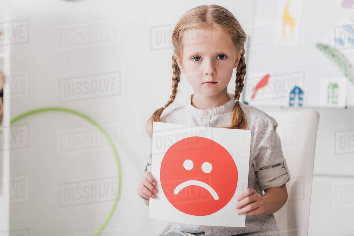 Close-up portrait of lonely little child holding sad face symbol ...