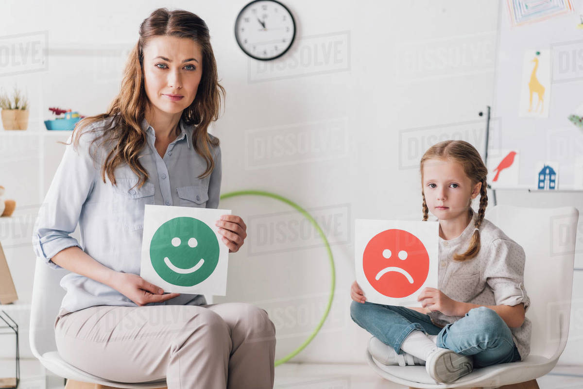 Adult psychologist and child holding happy and sad emotion faces cards ...
