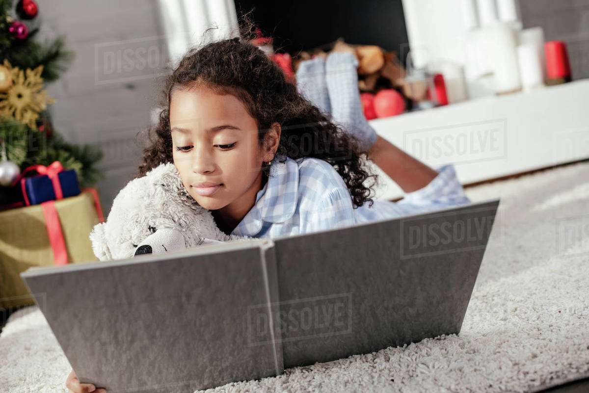 adorable african american child in pajamas with teddy bear reading book ...