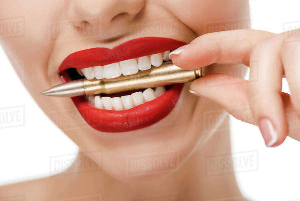 cropped shot of young woman holding bullet in teeth isolated on white ...