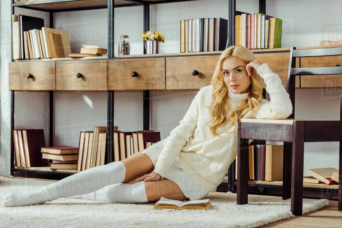 beautiful woman sitting on carpet with book in living room - Stock ...