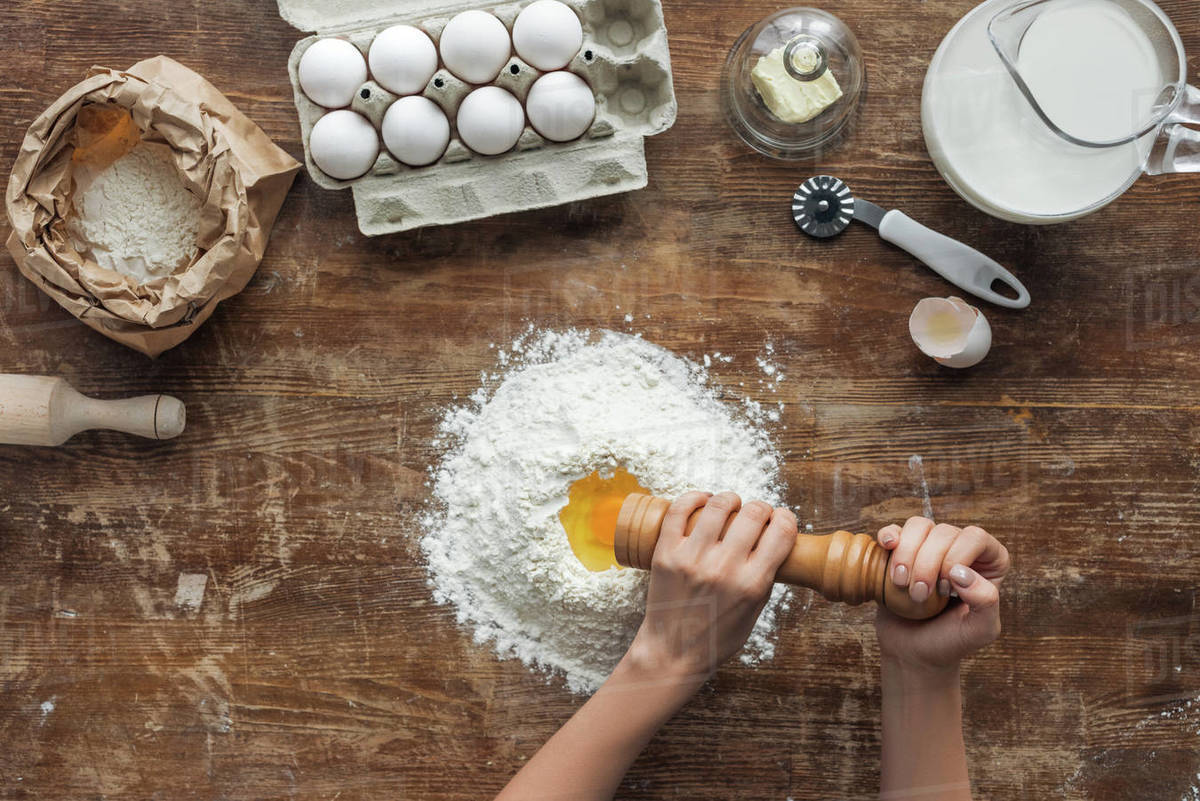top view of female hands adding salt to flour on wooden table - Royalty ...