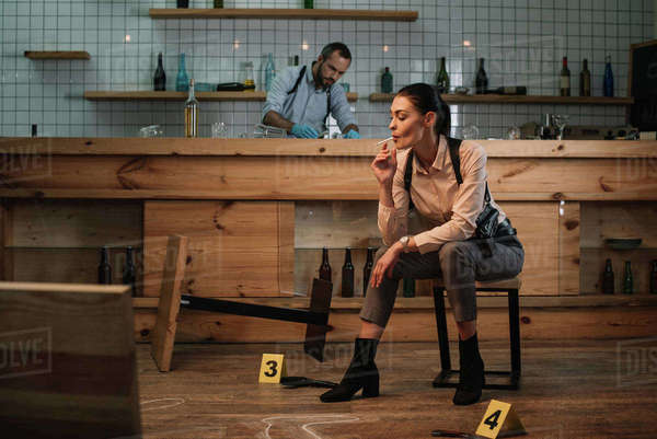 Cropped view of smoking female detective sitting at crime scene with ...