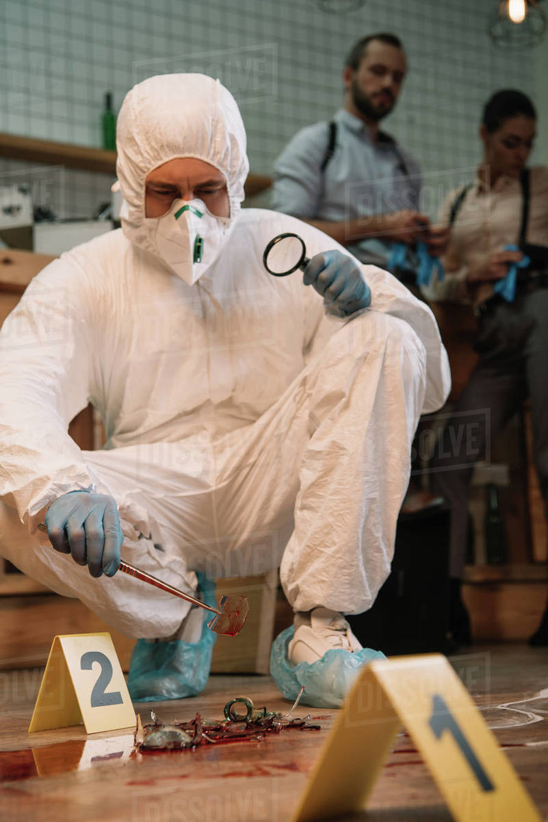 Concentrated forensic investigator examining evidence with magnifying ...