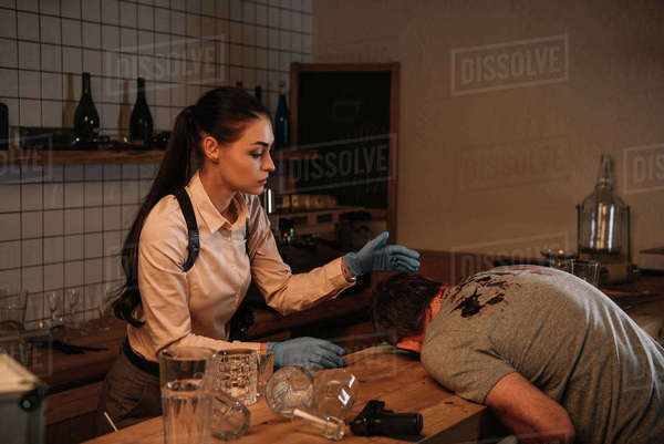 Concentrated female detective investigating dead body at crime scene ...