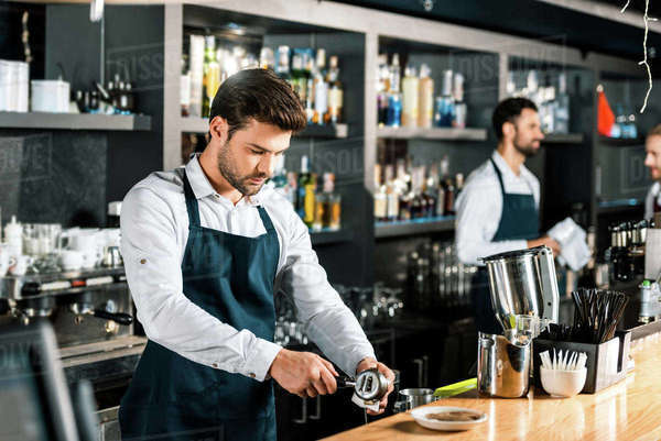 Handsome barista preparing coffee at wooden counter - Royalty-free ...