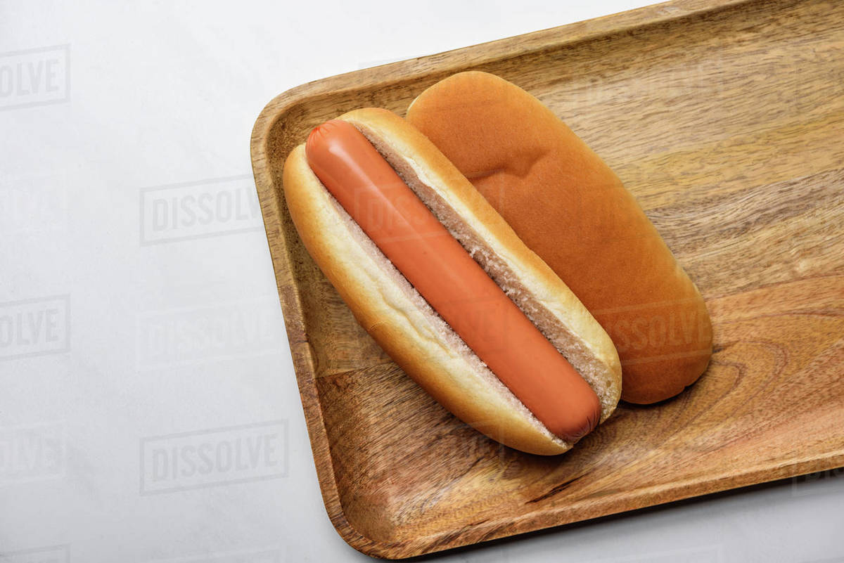Top view of hot dog on wooden board on white marble surface - Royalty ...