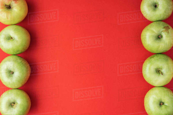 vertical frame of ripe green apples on red background - Stock Photo ...