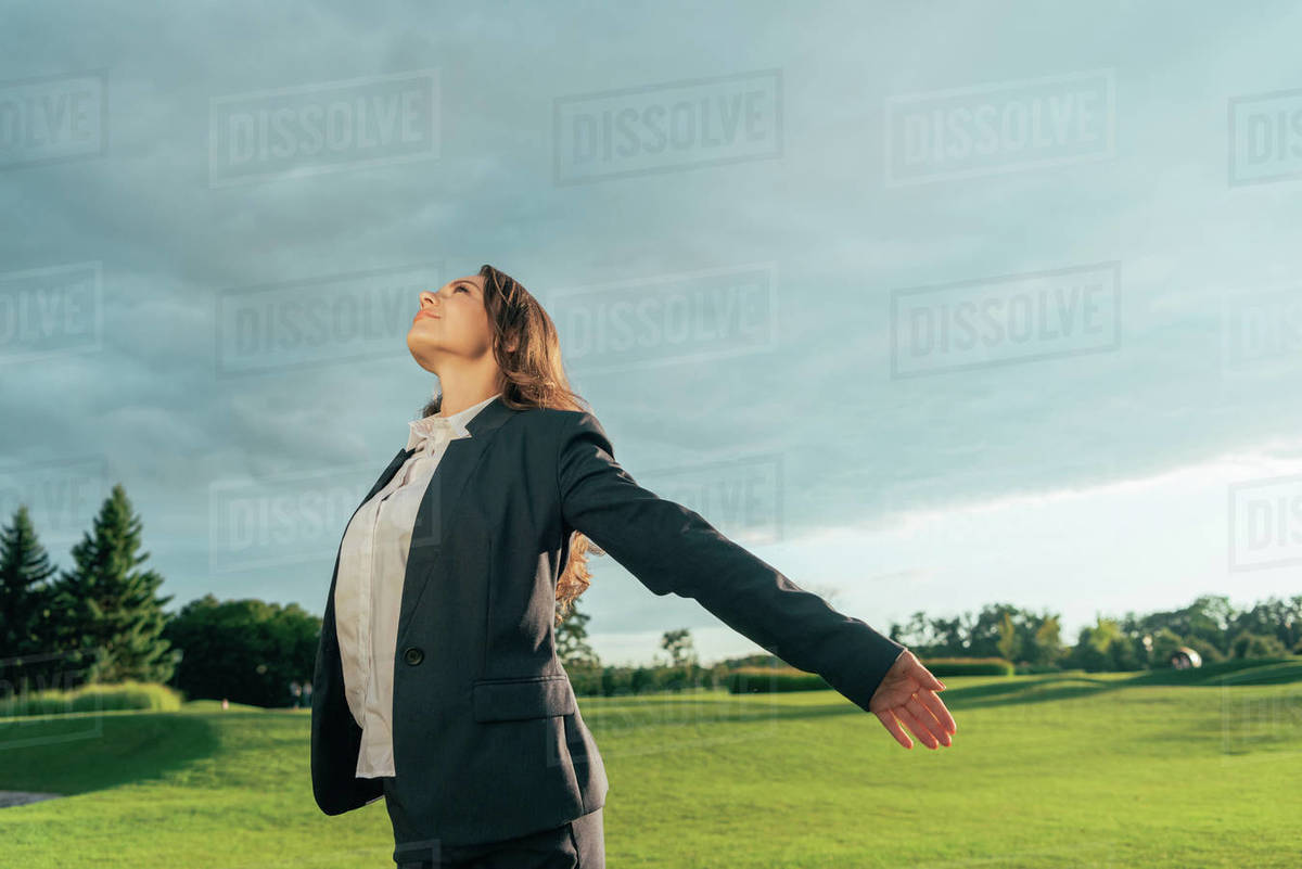 Side view of smiling businesswoman with outstretched arms standing in ...