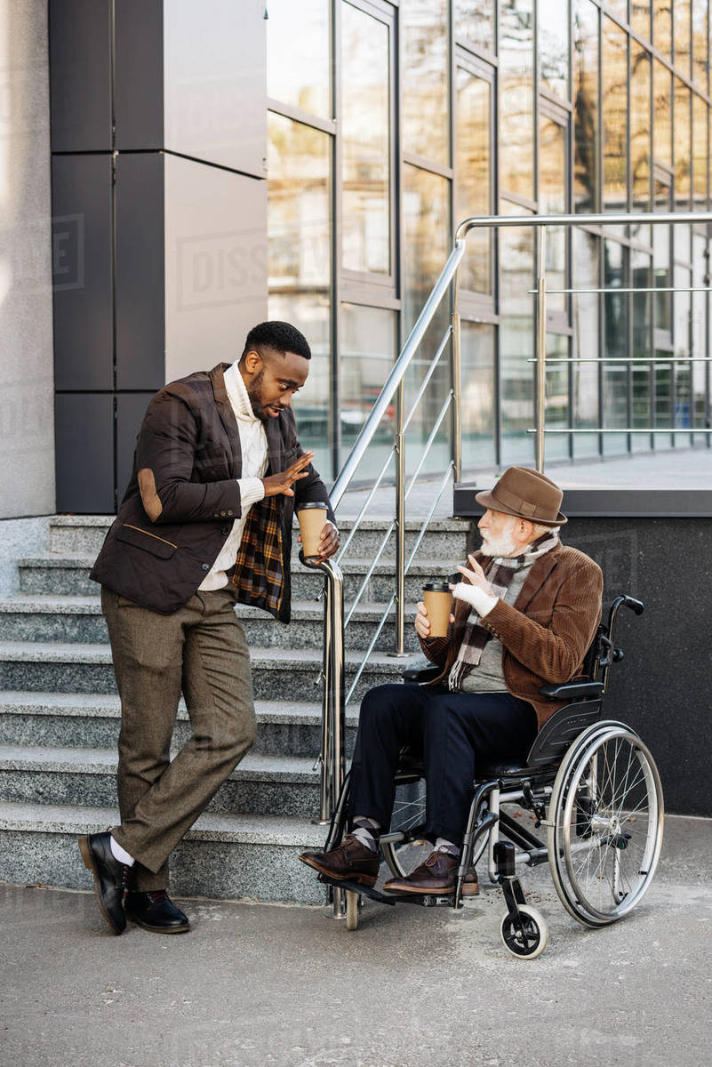 Senior Disabled Man In Wheelchair And African American Man Drinking