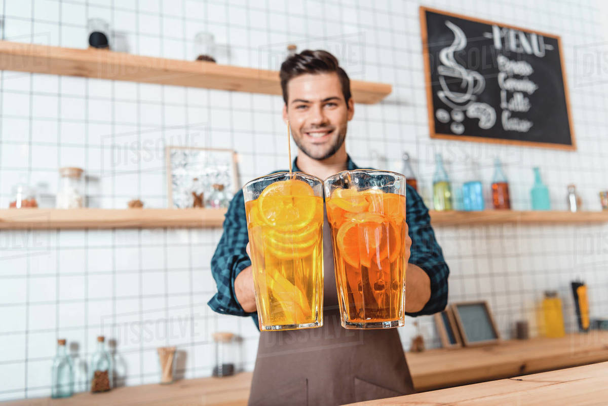 portrait of smiling bartender holding glass jars with refreshing ...