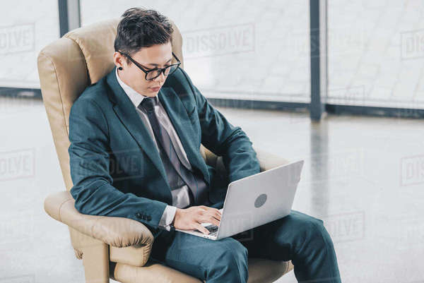 high angle view of young serious businessman sitting and using laptop ...
