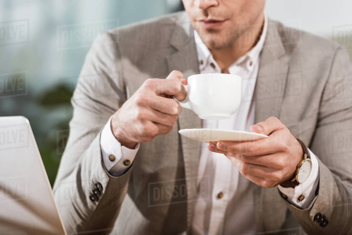 cropped shot of businessman drinking coffee at workplace - Stock Photo ...