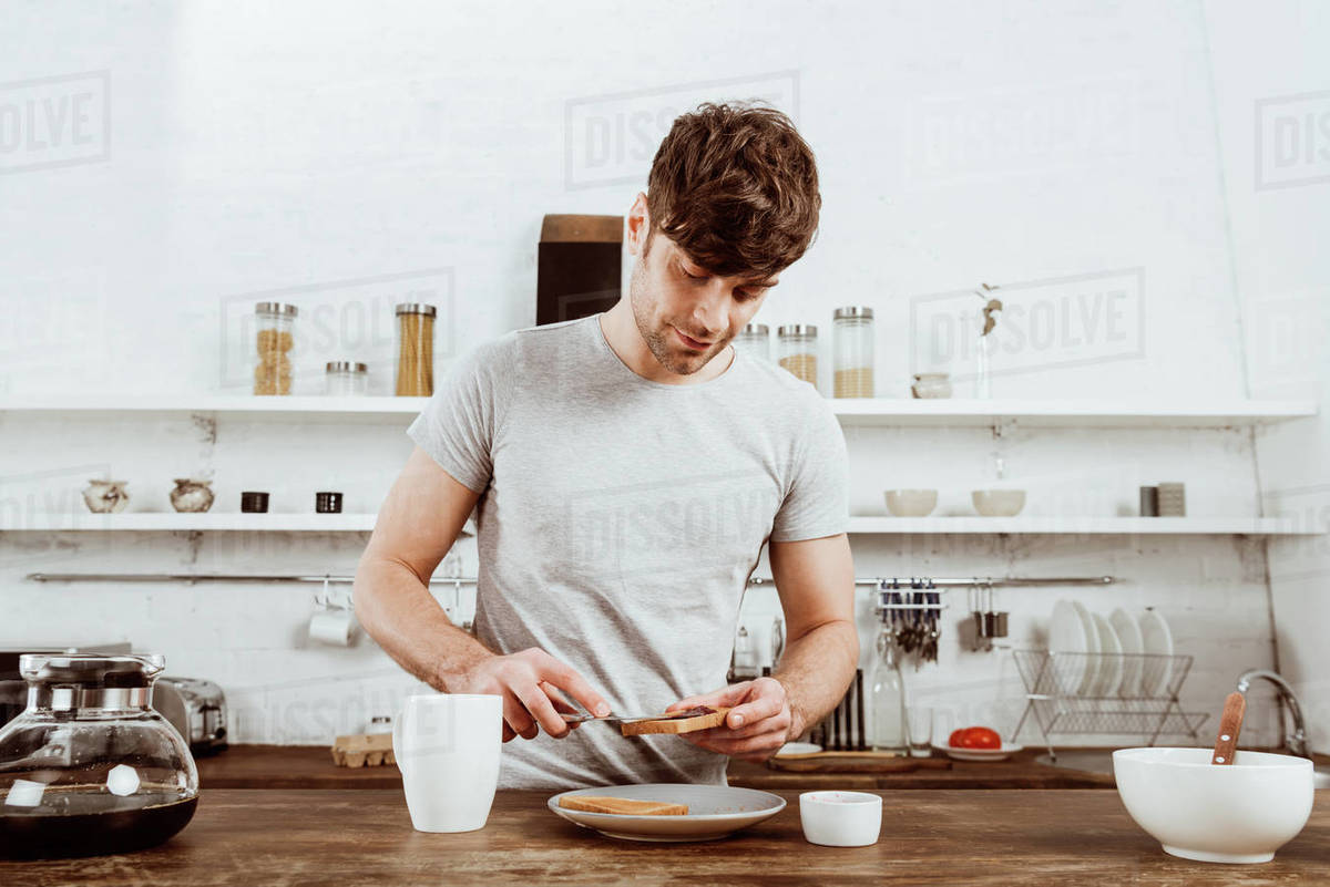 handsome man spreading toast by jam in kitchen at home - Royalty-free ...