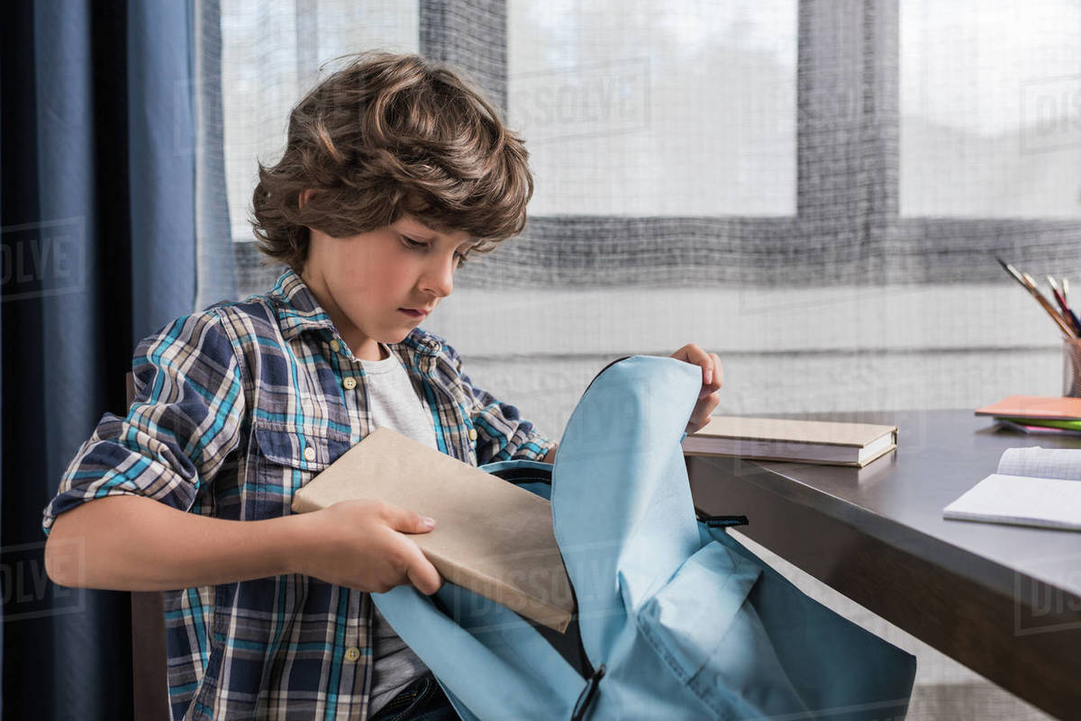 Side view of caucasian little boy packing backpack for school - Royalty ...