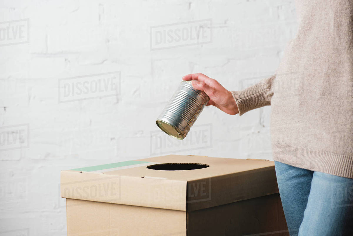 Partial view of woman throwing tin can in trash bin - Royalty-free ...