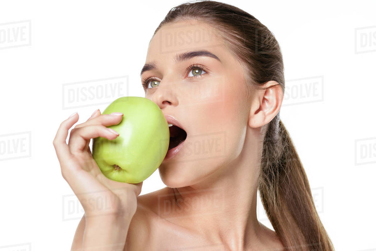 Beautiful young woman holding green apple and posing at camera isolated ...