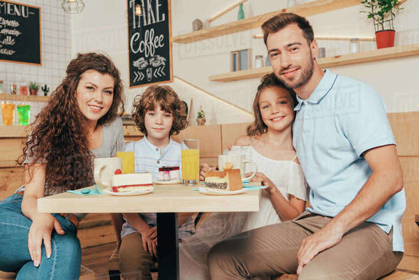 beautiful young family eating cakes in modern cafe - Royalty-free Stock ...