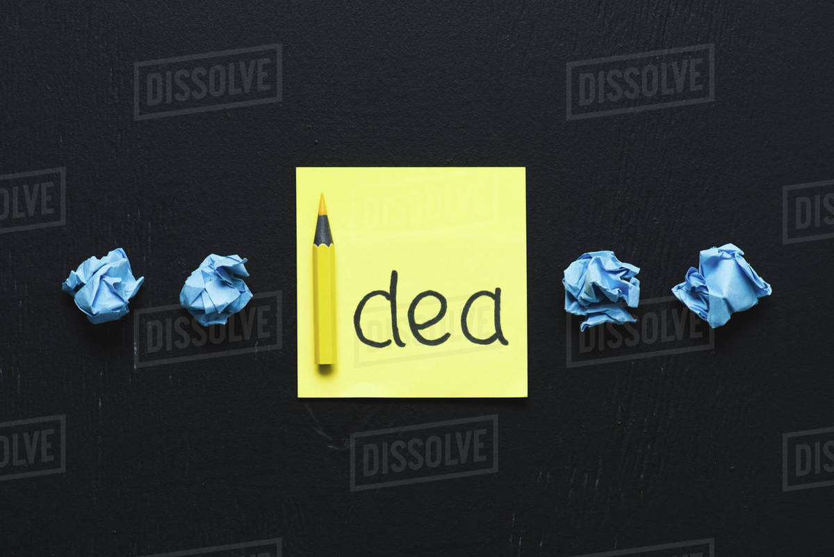 'idea' word written on sticky note and blue crumpled paper balls on ...