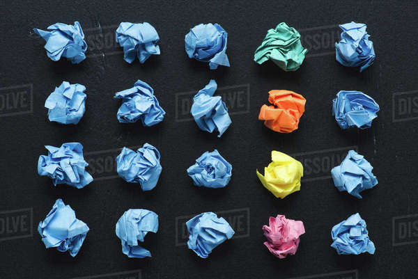 top view of crumpled paper balls with row of colorful ones on black ...