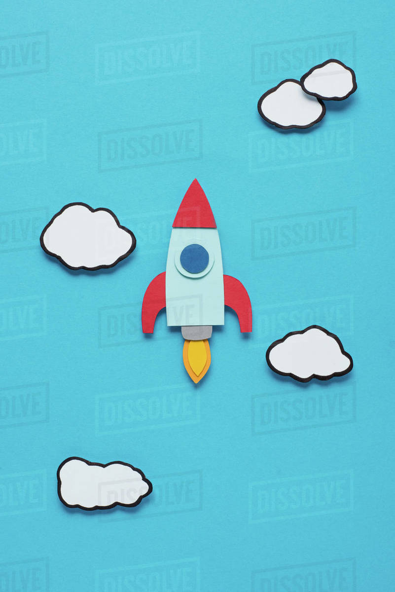 top view of paper rocket with clouds on blue background, setting goals ...