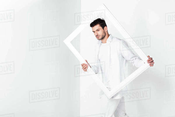 handsome adult man in total white holding frame - Stock Photo - Dissolve