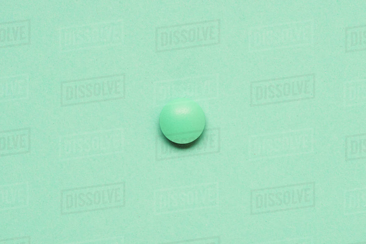 Top view of round green tablet on green background - Stock Photo - Dissolve