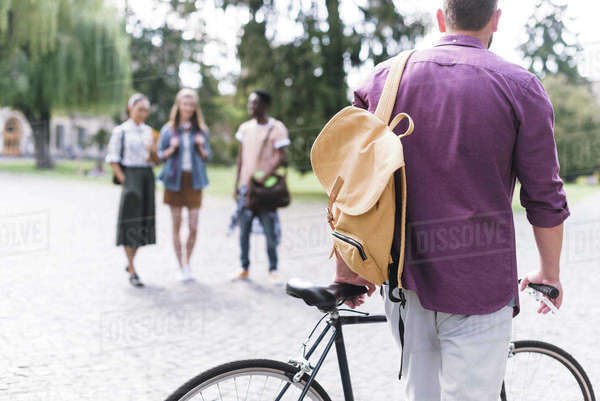 Back view of young man with bicycle and backpack in park - Royalty-free ...