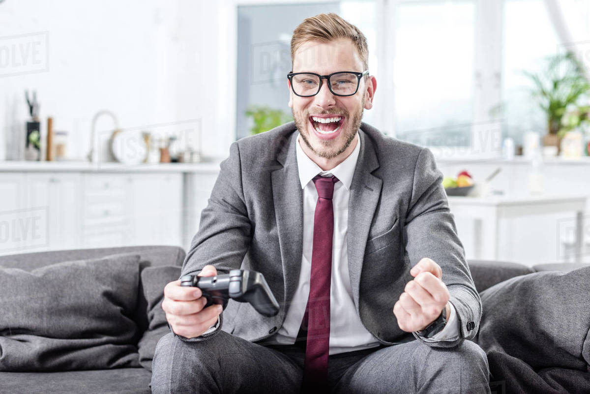 excited businessman holding console and playing video game at home ...