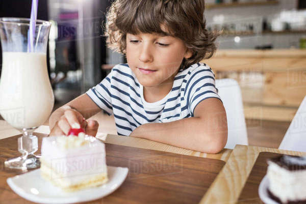 Cute little boy with piece of cake in cafe - Royalty-free Stock Photo ...