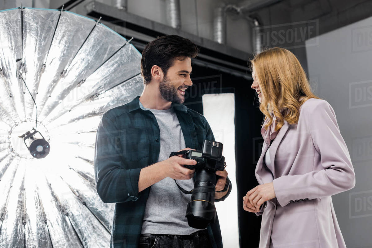 Smiling young photographer and model checking photos and talking in ...