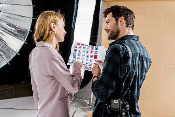 Back view of young photographer and model holding photos and smiling ...