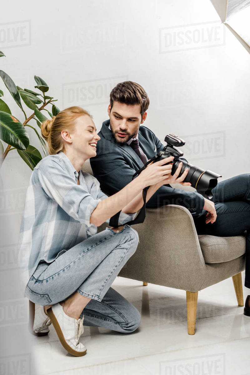 Smiling female photographer and handsome businessman using camera in ...