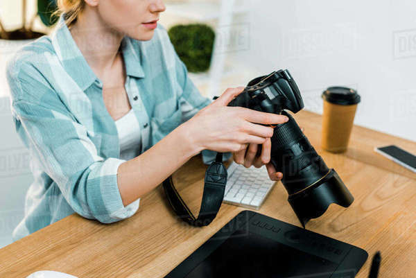Cropped shot of young female photographer working with camera in office ...