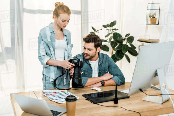 Professional young photographers using photo camera and discussing ...