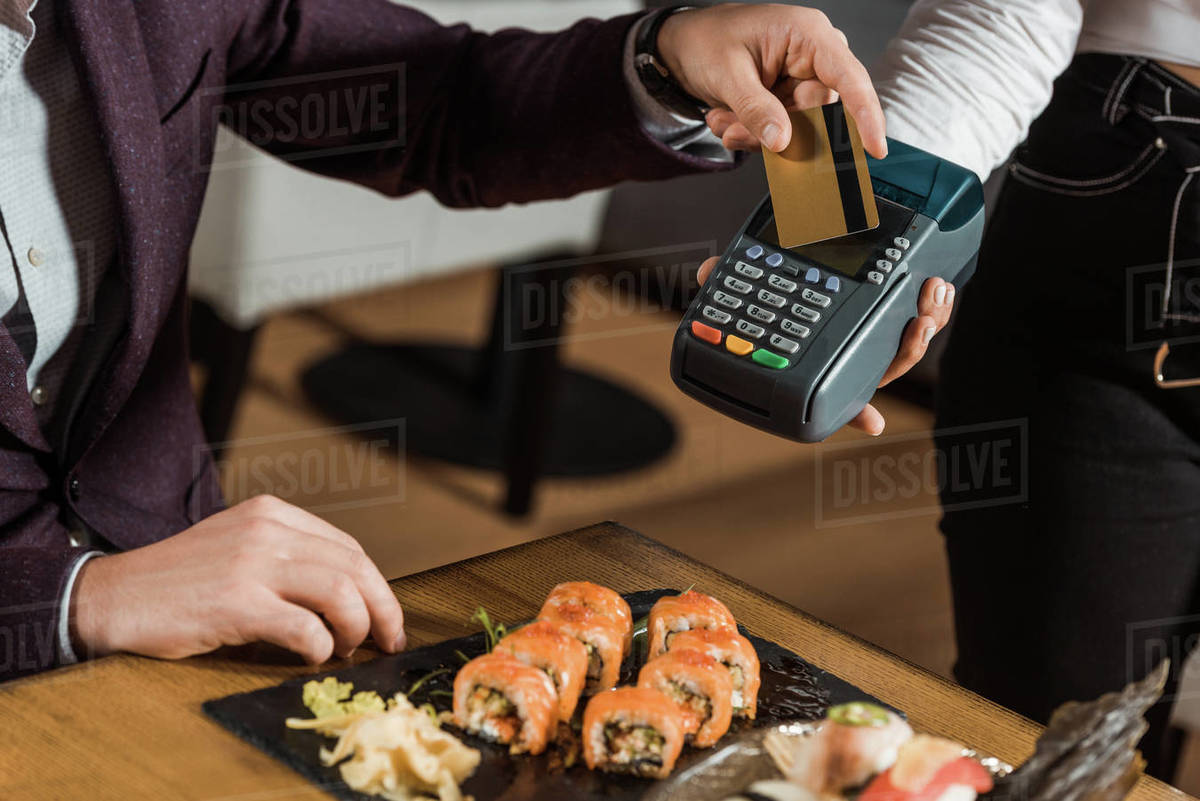 Partial view of man paying by credit card for dinner in restaurant ...