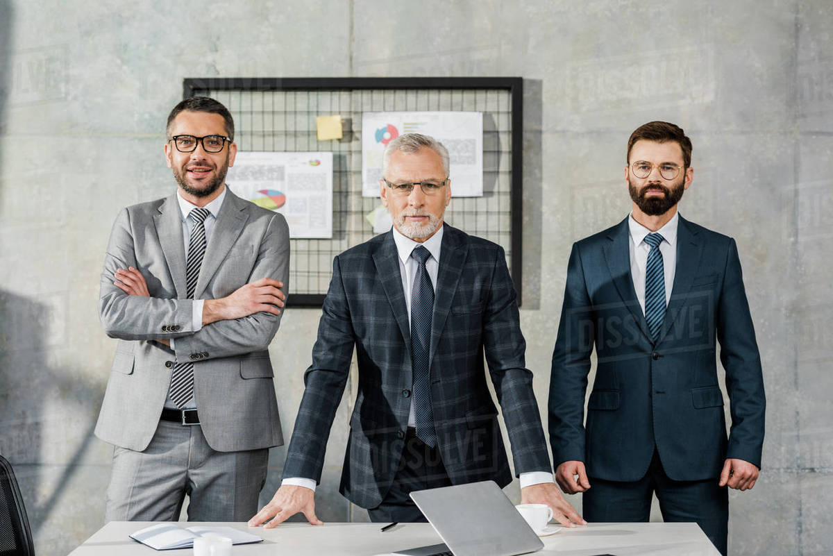 Three confident professional businessmen in formal wear standing ...