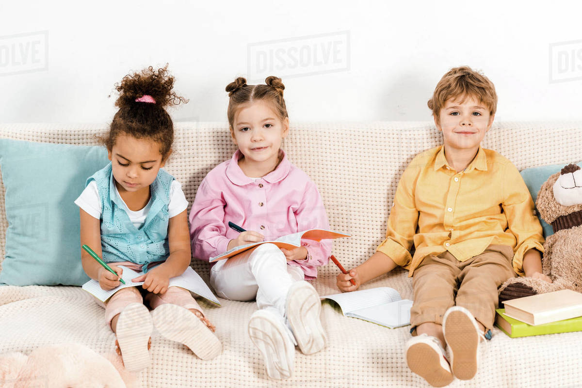 Cute happy children sitting on sofa and learning together - Royalty ...