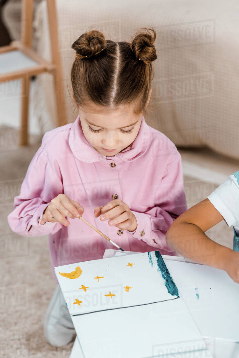 High angle view of adorable little child drawing picture with paints ...