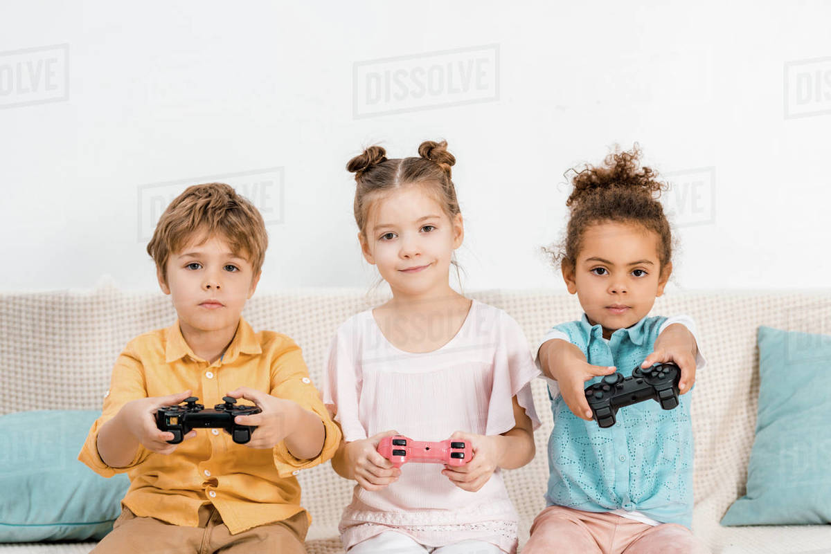 Cute little kids playing video game with joysticks and looking at ...